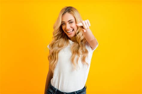 Blonde Woman Smiling And Pointing In Front Of Yellow Background Stock
