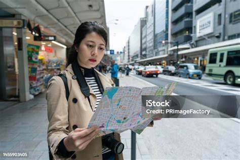 봄에 일본 교토로 여행하는 동안 길가 버스 정류장에서 집중적으로 경로 지도를 읽는 아시아 중국 소녀 관광객의 초상화 버스 정류장