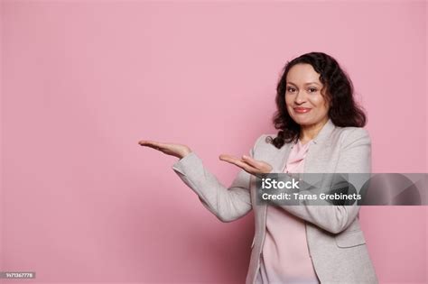 매력적인 중년 갈색 머리 여자 그녀의 손에 광고를 위한 상상의 복사 공간을 들고 손바닥 고립된 분홍색 배경 손바닥을 위로에 대한