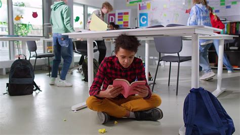 Siswa Remaja Afrikaamerika Membaca Buku Duduk Di Bawah Meja Di Kelas