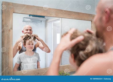 Bald Dad And His Long Haired Teenager Son In Bathroom In Front Of The