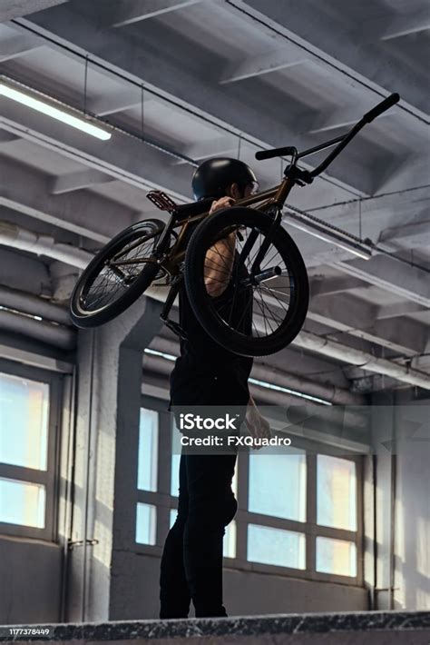 자전거를 들고 실내의 스케이트 파크에서 멀리 바라보는 보호 헬멧을 착용한 전문 Bmx 라이더 수직 사진 Bmx 자전거타기에 대한