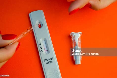 주황색 배경에서 코로나바이러스에 대한 테스트 매트 한 배경에 민감한 스트립 밝은 빨간 매니큐어와 소녀는 테스트를 위해 혈액 한