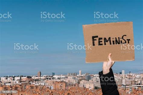 한 여성의 손에는 하늘과 도시를 배경으로 페미니스트라는 단어가 적힌 표지판을 들고 있다 페미니스트 개념 공간을 복사합니다 거리에 대한 스톡 사진 및 기타 이미지 Istock