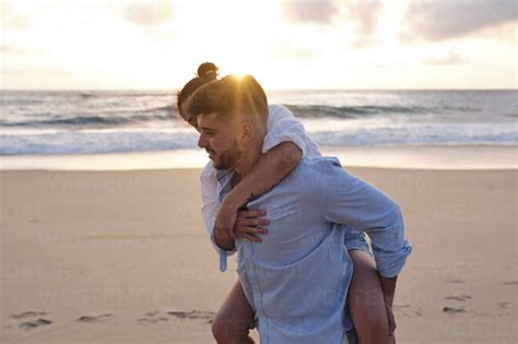 Mann Nimmt Seine Freundin Am Strand Bei Sonnenuntergang Huckepack