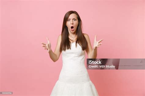 하얀 웨딩에 열린된 입으로 화가 충격된 신부 여자의 초상화 서 확산 손에 핑크 파스텔 배경에 고립 된 드레스 결혼식 축 하