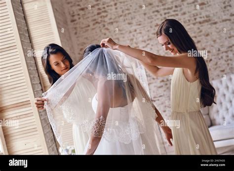 Last Preparations Bridesmaids Helping Bride To Put On A Veil While