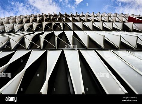 White Triangular Window Shades Creating A Dynamic Pattern On A Contemporary Building Facade