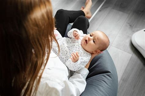 La madre cuida al bebé recién nacido en casa mamá sostiene a su pequeña hija de dos meses en sus