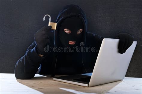 Hacker Man In Black Hood And Mask With Computer Laptop Hacking System In Digital Intruder Cyber