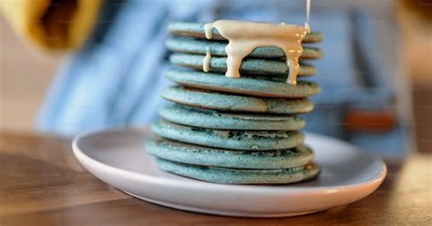 파란색 앞치마를 입은 여자가 나무 테이블에 카라멜 수즈와 함께 파란색 팬케이크를 붓는다 수제 맛있는 음식 슈로브타이드 축하 사진 Unsplash의 음식 이미지