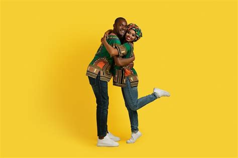 Encantadora pareja africana en trajes nacionales abrazándose en