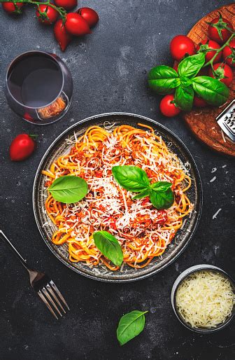 강판에 간 파마산 치즈와 키안티 레드 와인 잔을 뿌린 그린 바질을 곁들인 토마토 소스에 다진 고기를 곁들인 볼로네제 스파게티 또는 파스타 어두운 테이블 평면도 가루로 빻은에