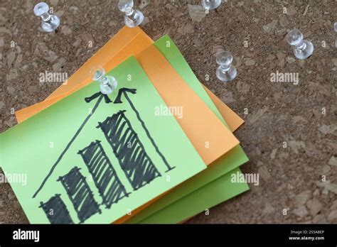 Close Up Of Pin And Hand Drawn Business Strategy Graph Chart On Sticky Note With Cork Board As