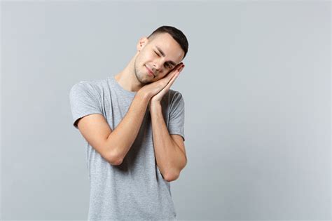 캐주얼 휴식에 젊은 남자를 깜박 얼굴 가까이 손을 자 고 스튜디오에서 회색 배경에 고립 된 눈을 유지 사람들은 진심으로 감정