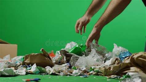 A Closeup Of Hands Sorting Recyclables On A Green Surface Stock Image