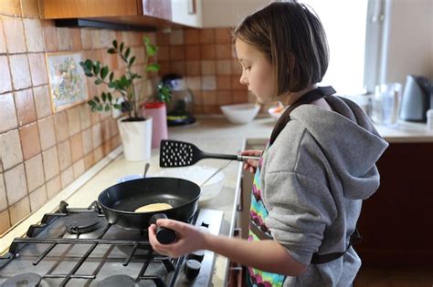 Premium Photo A Girl Cooks Pancakes In The Kitchen