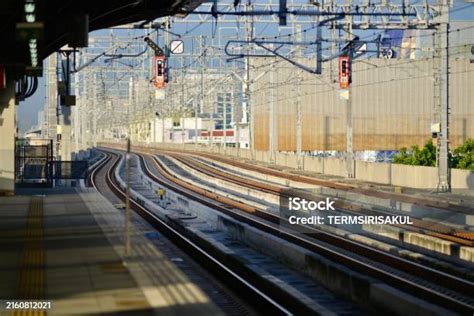 텅 빈 철로가 멀리서 구부러져 있는 기차역 플랫폼의 사진 이 이미지는 소실점으로 이어지는 평행선과 함께 역의 조용하고 질서 정연한 분위기를 포착합니다 0명에 대한 스톡 사진