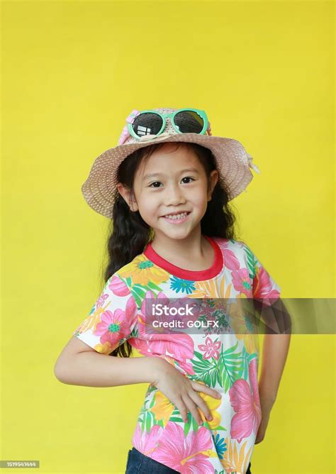 웃고 있는 사랑스러운 작은 아시아 소녀는 꽃무늬 여름 드레스를 입고 모자와 선글라스를 착용하고 노란색 배경에 포즈를 취한다 휴일과 여름 패션 컨셉 4 5세에 대한 스톡 사진