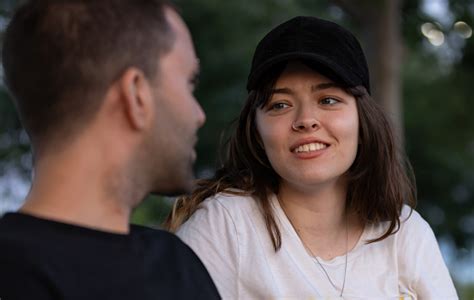 Young Couple Is Sitting On The Public Park Bench And Talking Each Other