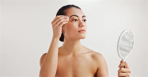 여성 거울 및 오일 스포이드 스튜디오에서 스킨 케어 체크 또는 흰색 배경으로 빛나는 결과 소녀 모델 및 유리 혈청 또는 아름다움 화장품 또는 변화를 위한 반사가 있는 액체를