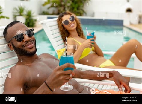 Couple Having Cocktail Drink While Relaxing On A Sun Lounger Stock