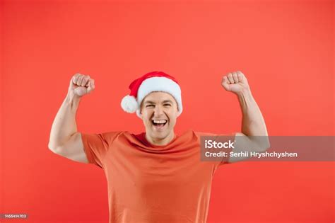 산타 모자를 쓴 행복하고 흥분된 남자의 초상화 기뻐하고 무언가를 얻고 새해를 축하하고 빨간색 배경 위에 서 있다 12월에 대한
