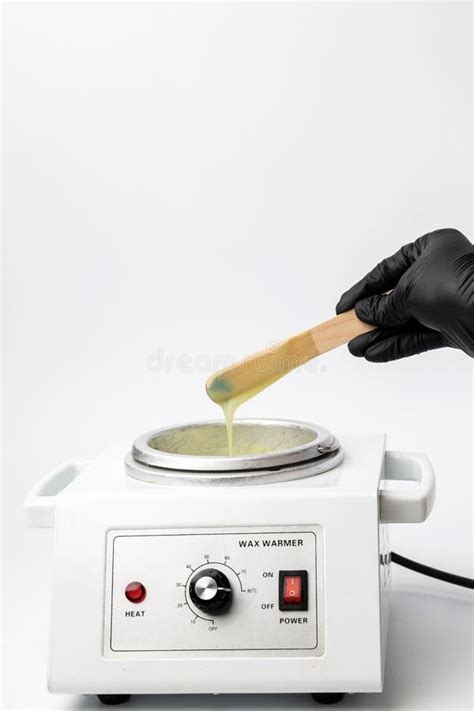 Human Hand Holding Wooden Sticks With Wax Over Wax Melter Stock Image