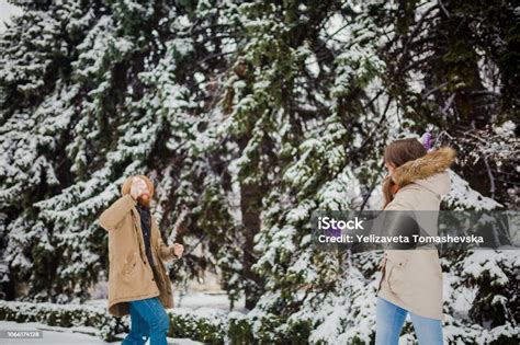수염과 여자와 어린 백인 소년 데이트가 야외에서 눈 덮인 침 엽 수 나무 놀이 눈덩이 던져 눈의 배경에 대해 겨울 공원에서