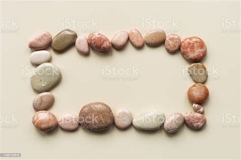 복사 공간이있는 베이지 색 배경에 바다 조약돌 돌의 미적 최소 프레임 자연적인 매끄러운 돌 파스텔 분홍색 노란 색깔에서 정사각형