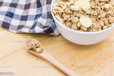 건강한 아침 식사 견과류와 나무 숟가락과 귀여운 직물나무 테이블에 흰색 타격에 건조 바나나와 그래놀라 갈색에 대한 스톡 사진 및