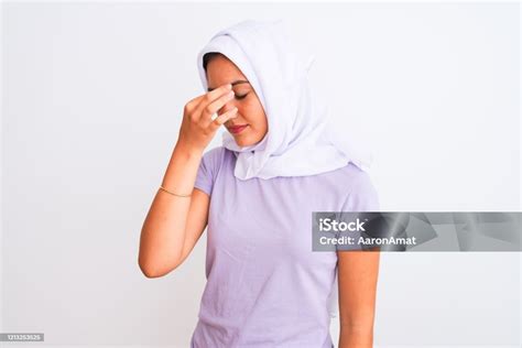 고립 된 흰색 배경에 서 히잡을 입고 젊은 아름다운 아라비아 소녀는 피로와 두통을 느끼는 코와 눈을 문질러 피곤 스트레스와 좌절