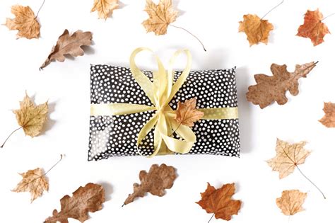 선물은 포장지로 감싸고 노란 리본으로 묶여 흰색 배경에 마른 단풍 나무 잎과 함께 놓습니다 생일 기념일 선물 기부에 축하의 가을 개념 0명에 대한 스톡 사진 및 기타 이미지