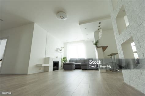 흰 벽과 바닥에 카펫이 깔린 쪽모이 세공 마루가있는 현대적인 스타일의 홀 베개 테이블 의자 냄비에 식물 고리 버들 세공 검은 램프 거울 사물함 선반이있는 소파가 있습니다 0