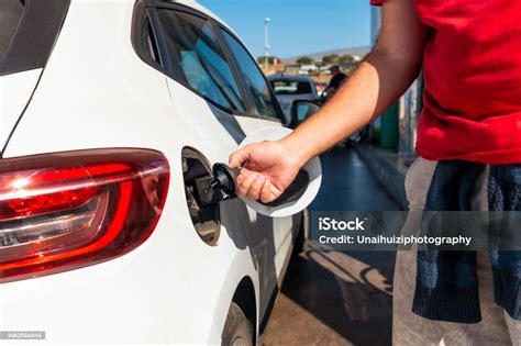 흰색 자동차에서 휘발유나 디젤 연료에 연료를 보급하기 위해 자동차 노즐을 여는 남자 교통 에너지 위기 석유 위기의 개념 가스