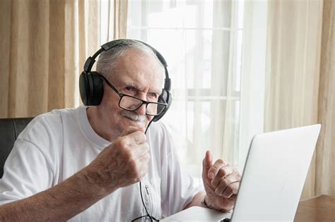 노트북으로 집에서 헤드폰을 착용 행복한 노인 안경을 쓴 회색 머리의 노인이 음악을 듣고 인생을 즐긴다 활동적인 노년기의 개념