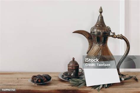 라마단 카림 정물 장식용 컵 아랍어 달라 커피 포트 및 빈 인사말 카드 모형 올리브 나뭇가지 은색 접시에 대추 과일 나무 테이블 흰 벽 무슬림 이프 타르 저녁 식사 커피