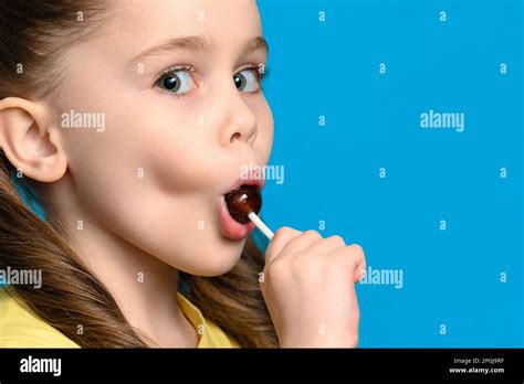 On A Blue Background A Girl Licks A Round Lollipop Close Up Caries