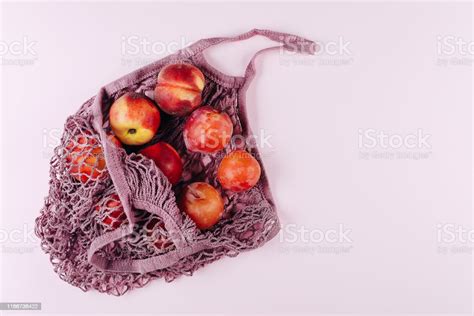 분홍색 배경에 과일 Plims와 복숭아 메쉬 쇼핑 백 상단보기 평평한 평신도 복사 공간 폐기물 제로 친환경 컨셉 가방에 대한