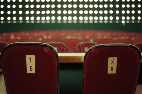 There Is A Row Of Vacant Empty Red Seats Positioned In A Theater Stock