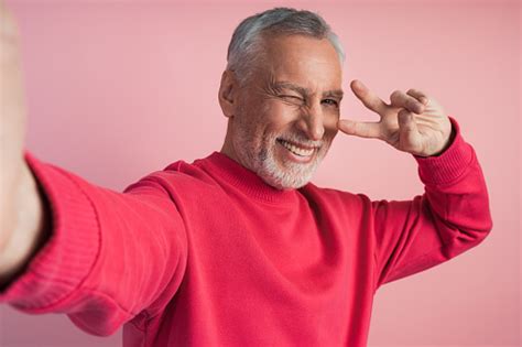 긍정적 인 남자는 V 표시 승리의 몸짓 평화 셀카 만들기를 보여줍니다 분홍색 배경 복사 공간 텍스트 장소에 포즈를 취하는