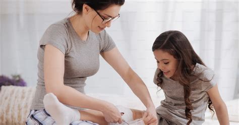 어머니의 보살핌을 즐깁니다 미소 짓는 어린 소녀는 집에 앉아서 웃고 있으며 어머니는 롤러를 잡고 다리에 붕대를 감고 있습니다 사진 Unsplash의 어머니 이미지