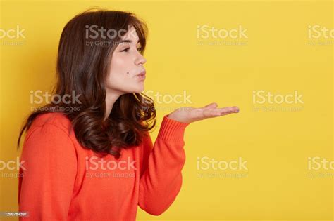 공기 키스를 보내는 꼬리치는 분위기와 꽤 매력적인 어두운 머리 여자의 프로필 사진 손바닥을 엽니 다 누군가에게 유혹 유혹 입술