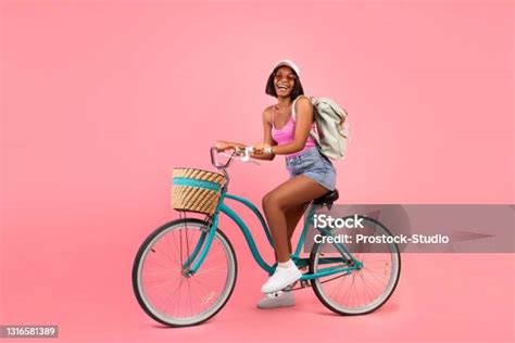 핑크 스튜디오 배경 위에 자전거를 타고 캐주얼 여름 옷에 사랑스러운 흑인 여성의 전체 길이 초상화 두발자전거에 대한 스톡 사진 및 기타 이미지 Istock