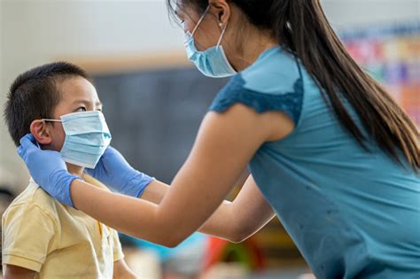 아이가 보호 얼굴 마스크를 착용하는 데 도움이 보육 촉진기 2명에 대한 스톡 사진 및 기타 이미지 2명 4 5세