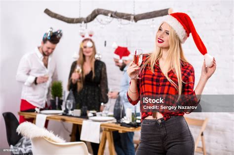 집에서 전경에 샴페인 한 잔과 젊은 여자의 초상화 감 금 소에 검은 청바지 산타 모자 빨간 셔츠에 아름 다운 금발 Political Party에 대한 스톡 사진 및 기타