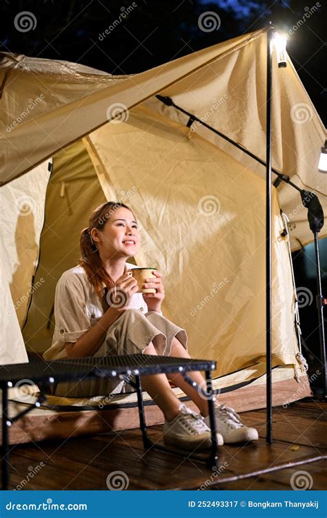 Asian Female Sitting In Front Of Her Tent Sipping Hot Coffee And