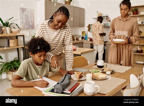 Mère Aidant Son Fils à Faire Ses Devoirs Quand Sa Fille Apporte Des