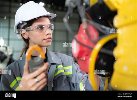 In The Robots Warehouse A Female Engineer Inspects The Electrical System Of Every Robotics Arm