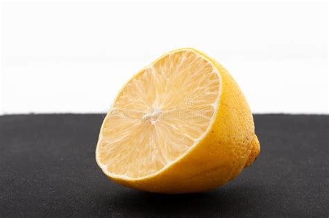 A Lemon Is Cut In Half And Is Sitting On A Black Surface Stock Image